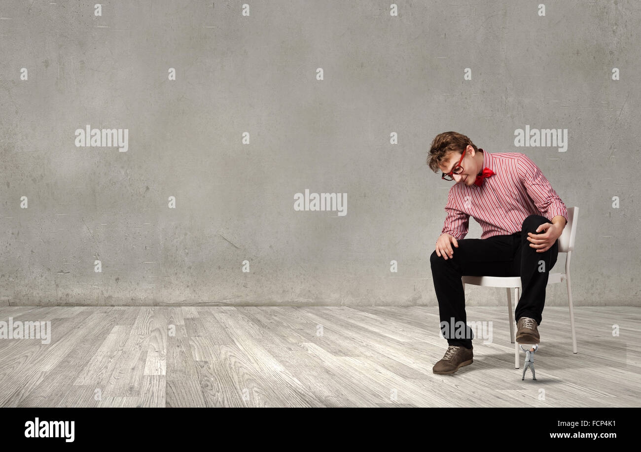 Guy sitting on chair and stepping on small business person Stock Photo ...