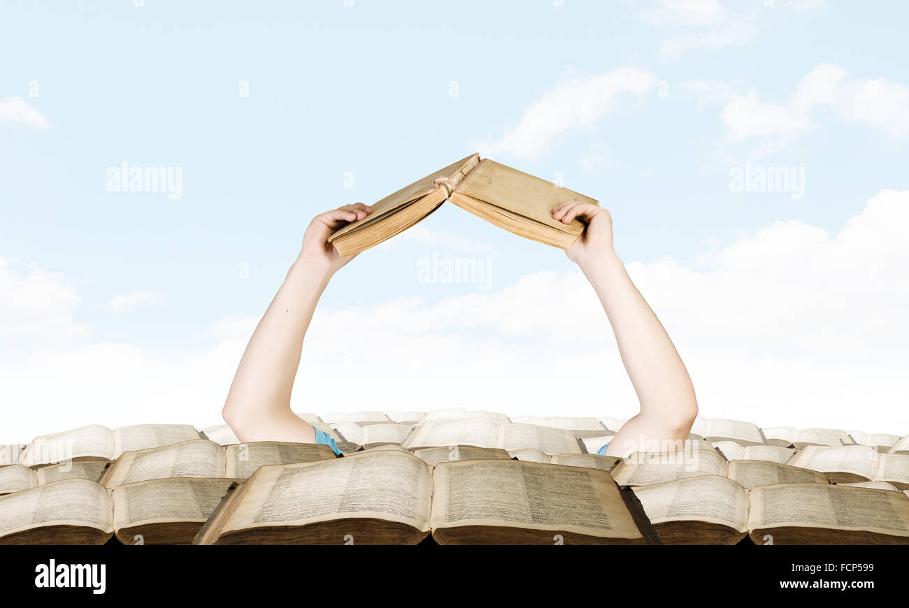 Hand with book reaching out from pile of old books Stock Photo - Alamy