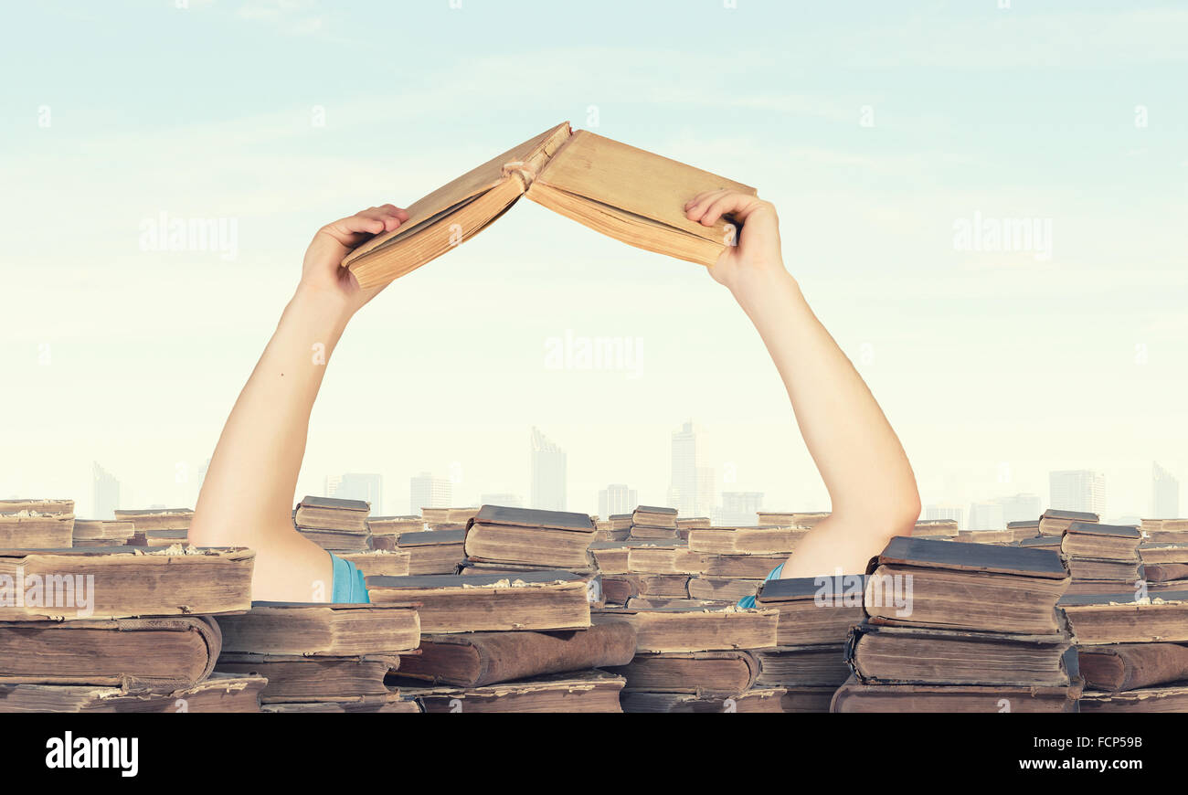 Hand with book reaching out from pile of old books Stock Photo - Alamy
