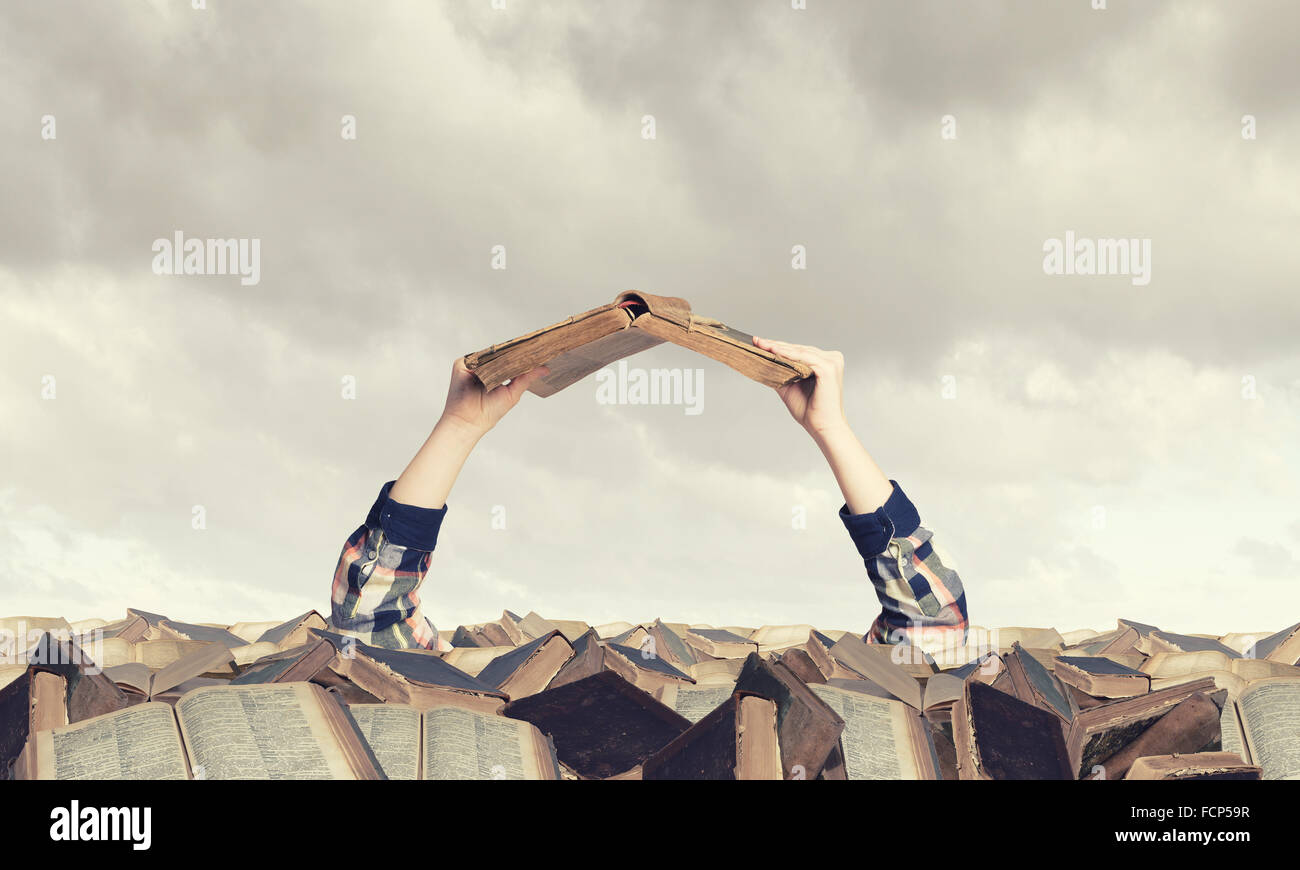 Hand with book reaching out from pile of old books Stock Photo - Alamy