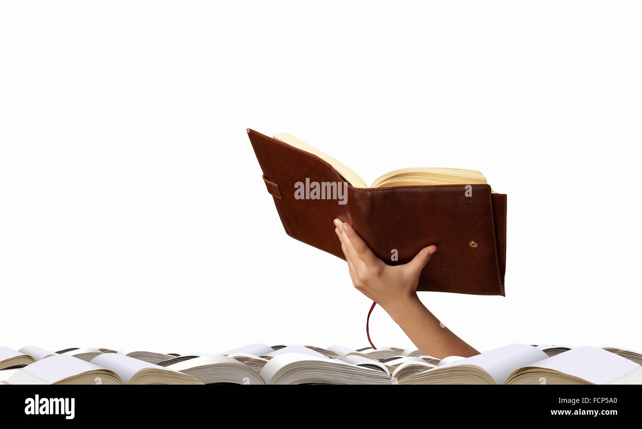 Hand with book reaching out from pile of old books Stock Photo - Alamy