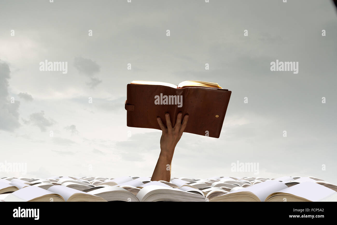 Hand with book reaching out from pile of old books Stock Photo - Alamy