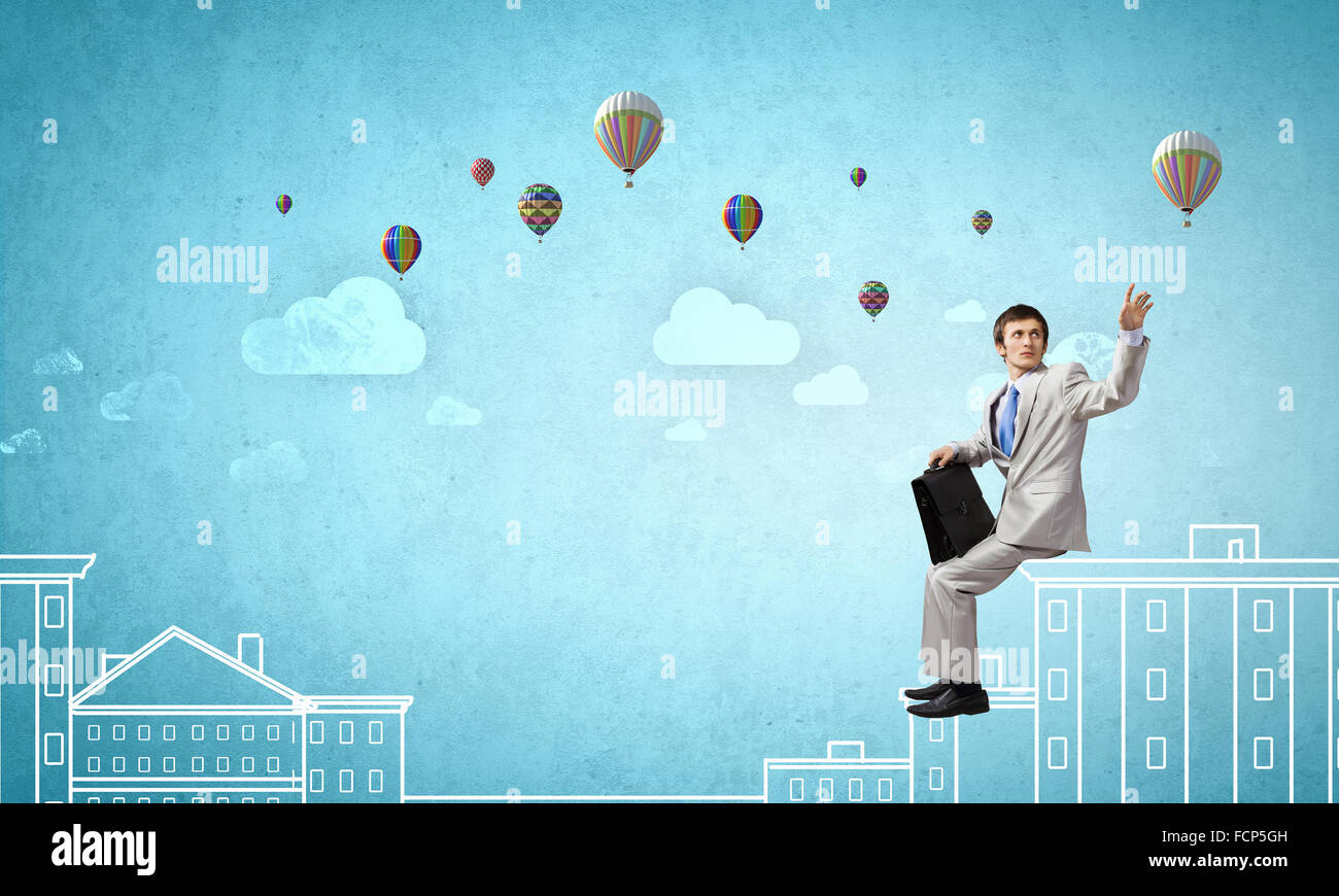 Businessman in white suit with briefcase sitting on building top Stock ...