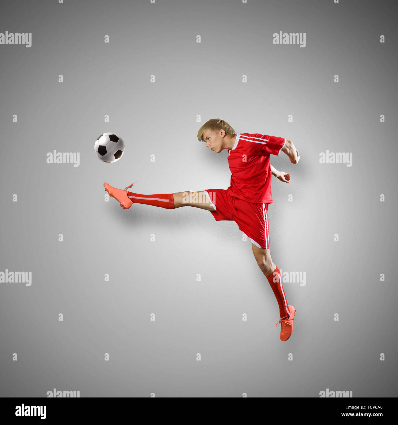 Handsome male football player jumping to hit the ball Stock Photo - Alamy