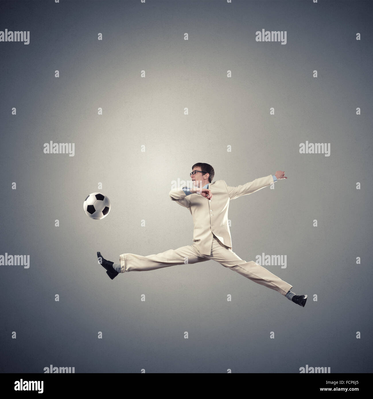 Businessman in suit jumping to hit soccer ball Stock Photo - Alamy