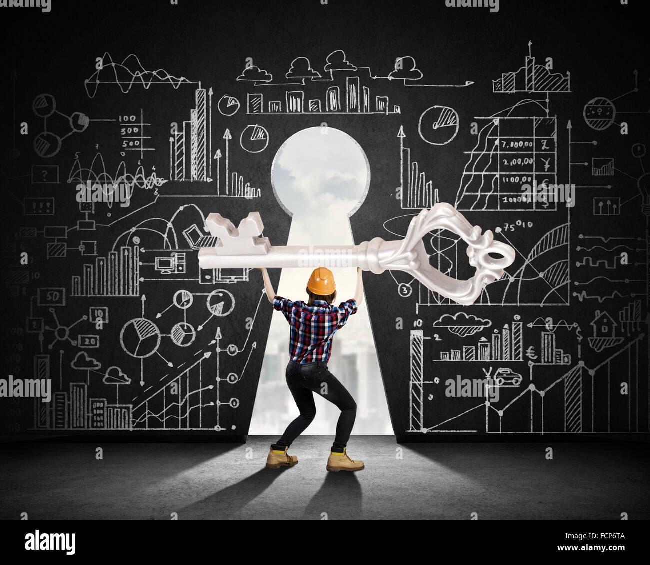 Young woman builder and keyhole at background lifting big key above ...