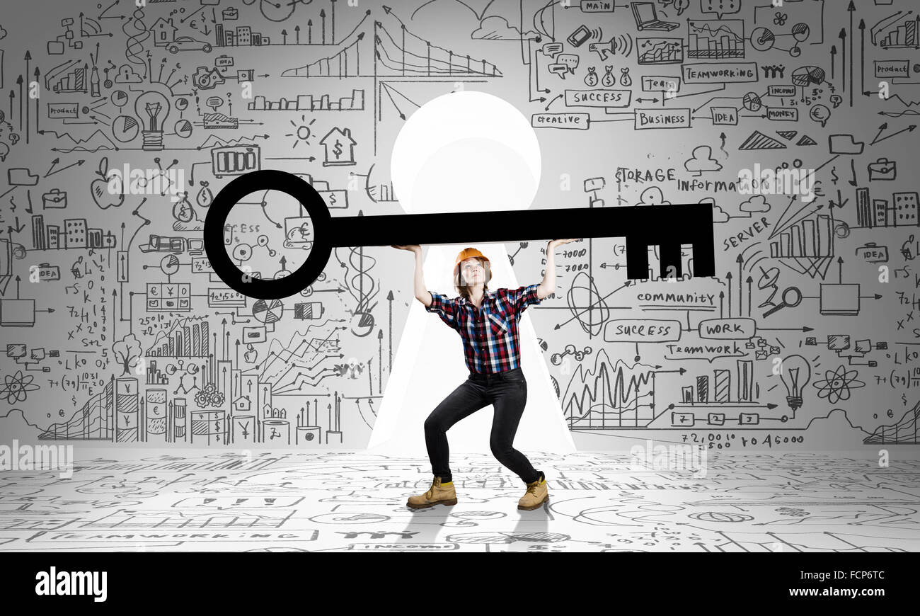 Young woman builder and keyhole at background lifting big key above ...