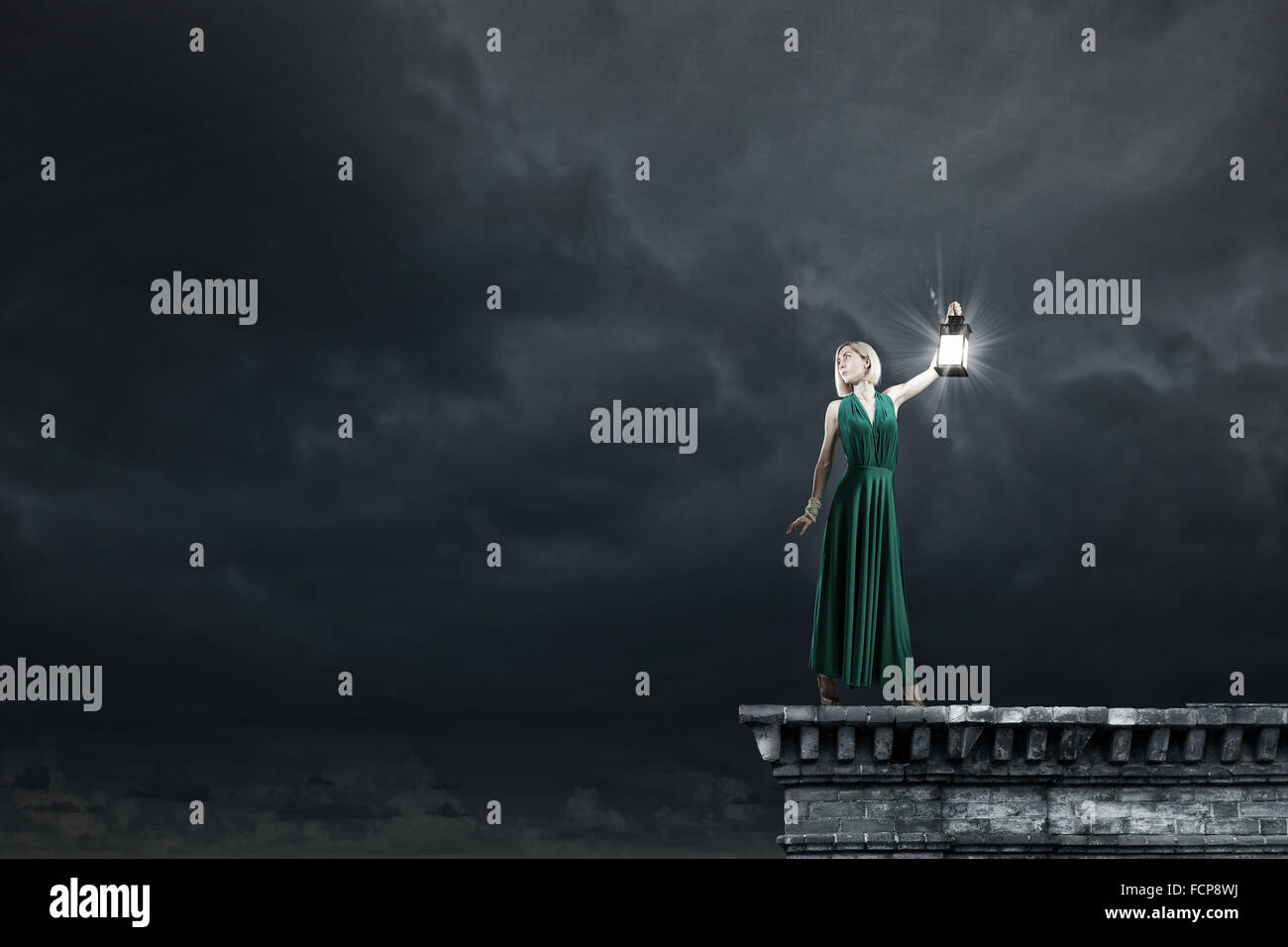 Young attractive woman in green dress with lantern walking in darkness ...