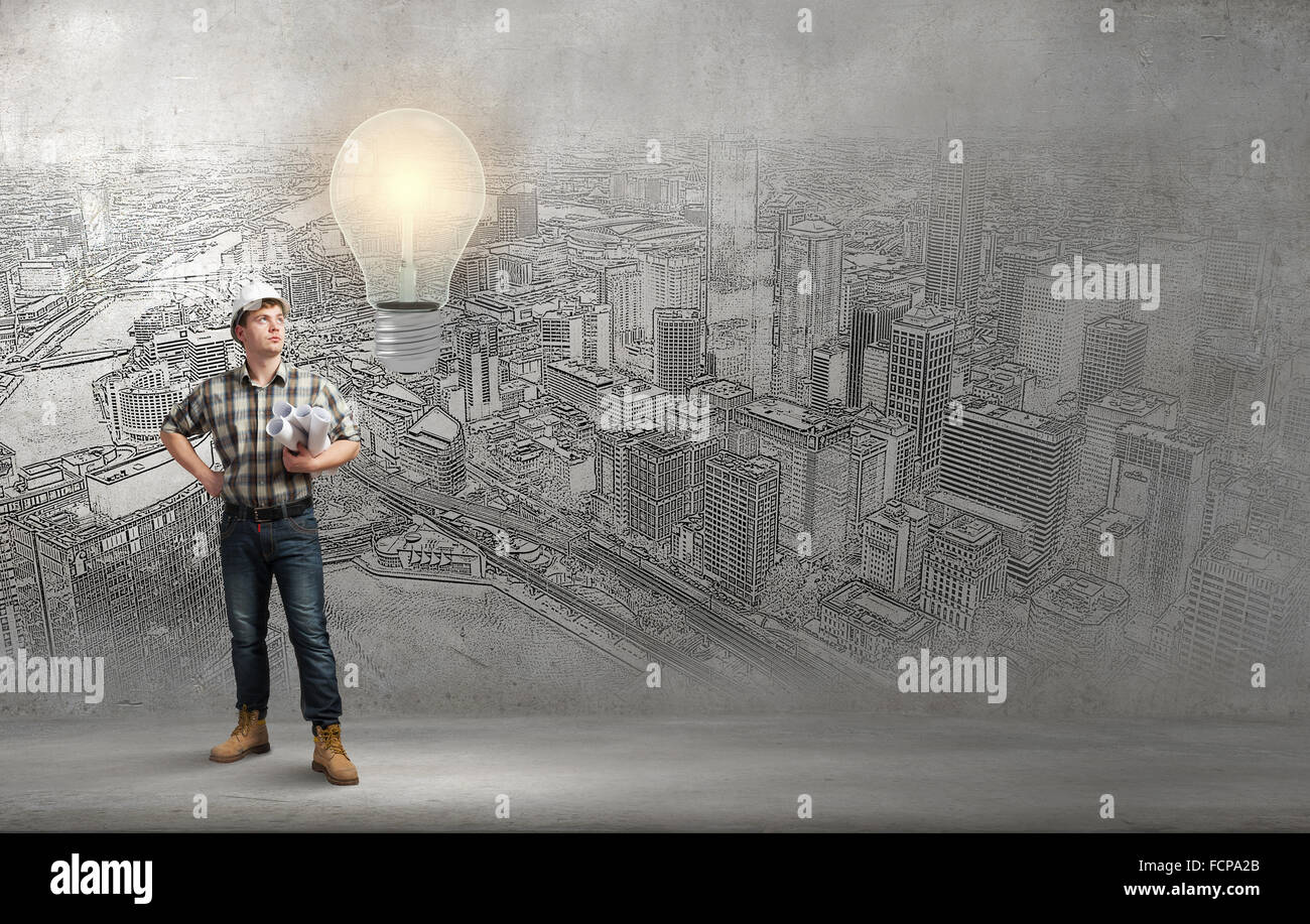 Young man builder looking thoughtfully at light bulb. Idea concept ...