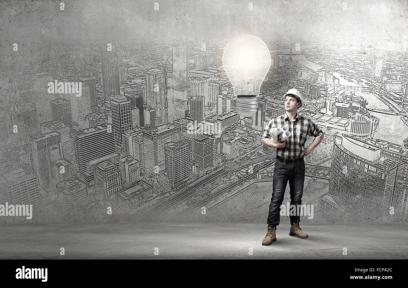 Young man builder looking thoughtfully at light bulb. Idea concept ...