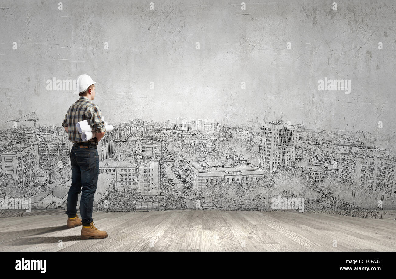 Young man builder looking thoughtfully at construction project. Idea ...