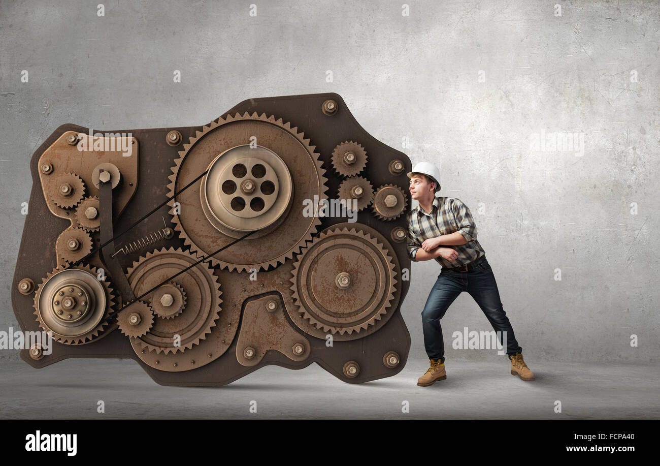 Young man builder making effort to move gears mechanism Stock Photo - Alamy