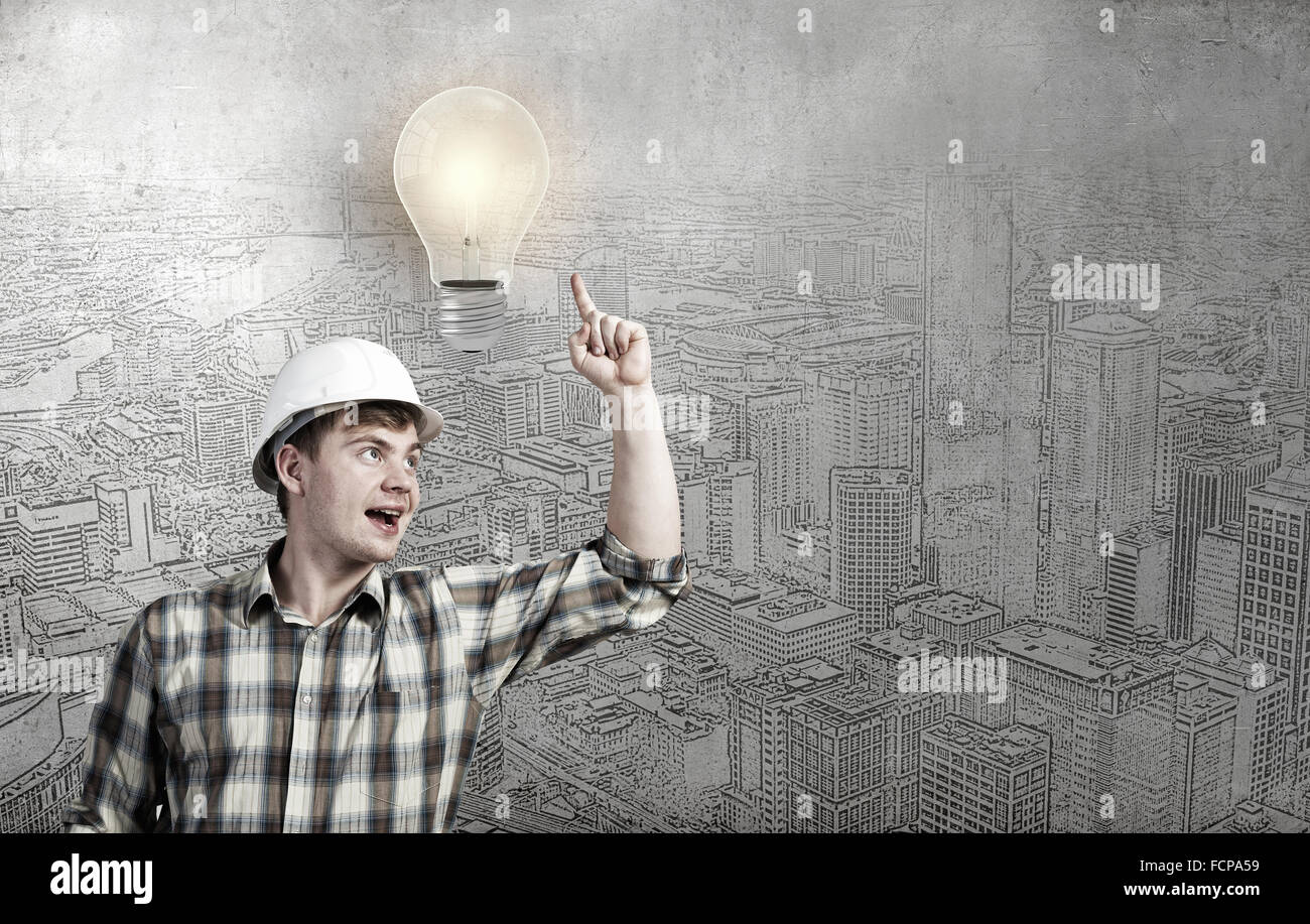 Young man builder looking thoughtfully at light bulb. Idea concept ...
