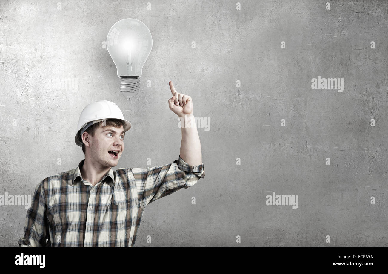Young man builder looking thoughtfully at light bulb. Idea concept ...