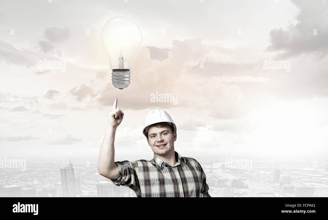 Young man builder looking thoughtfully at light bulb. Idea concept ...