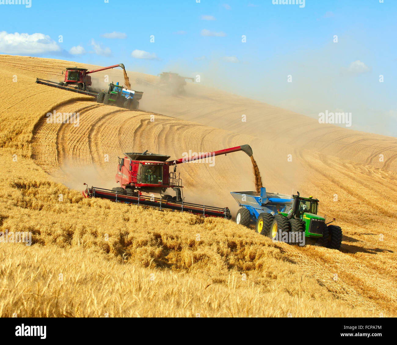 One or more combines offloading grain to a tractor pulled grain cart in ...