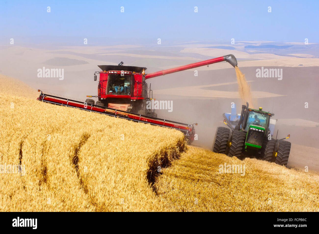 One or more combines offloading grain to a tractor pulled grain cart in ...