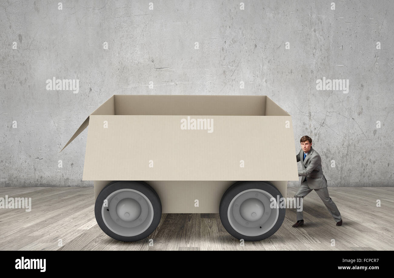 Young businessman pushing carton box on wheels Stock Photo - Alamy