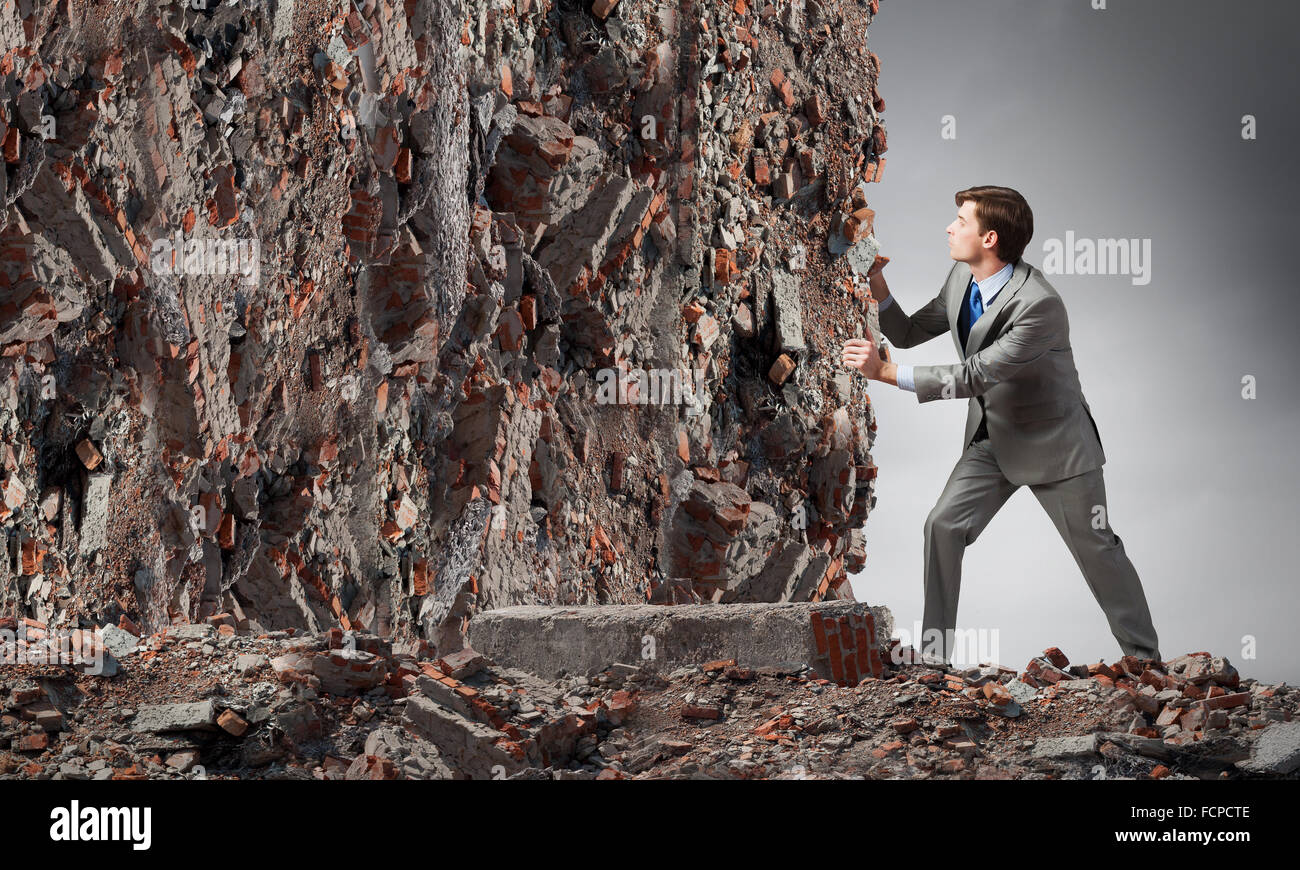 Businessman making effort to move stone wall Stock Photo - Alamy