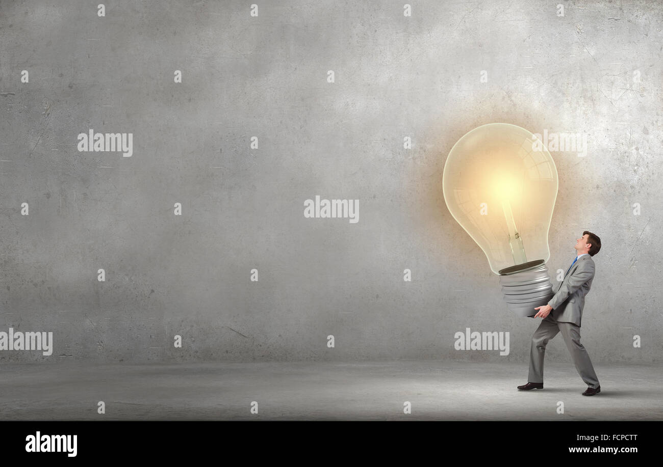 Young businessman carrying in hands big light bulb Stock Photo - Alamy