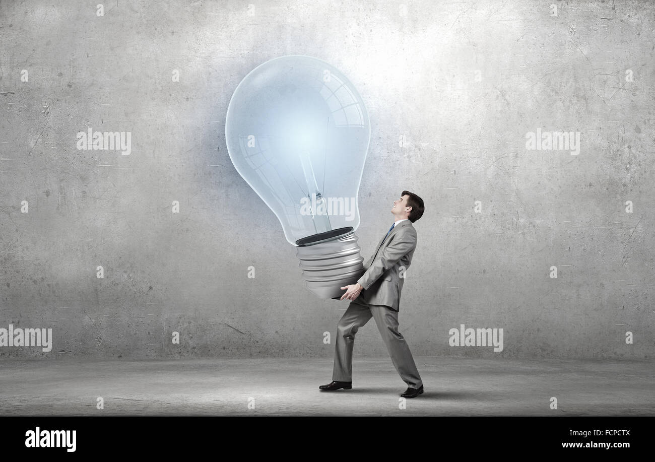 Young businessman carrying in hands big light bulb Stock Photo - Alamy