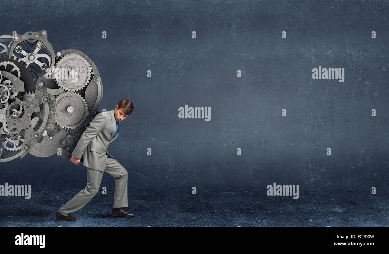 Young businessman carrying huge gears mechanism on back hi-res stock ...