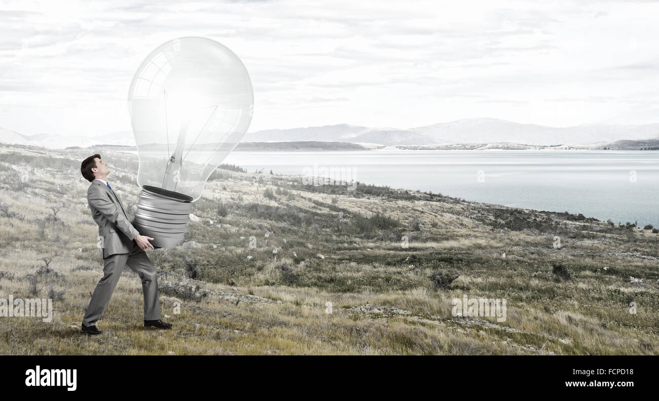 Young businessman carrying in hands big light bulb Stock Photo - Alamy