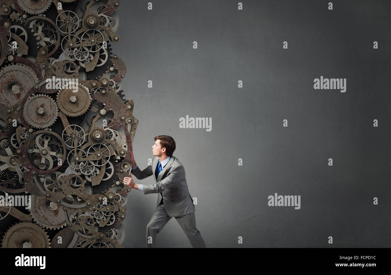 Young businessman carrying huge gears mechanism on back Stock Photo - Alamy