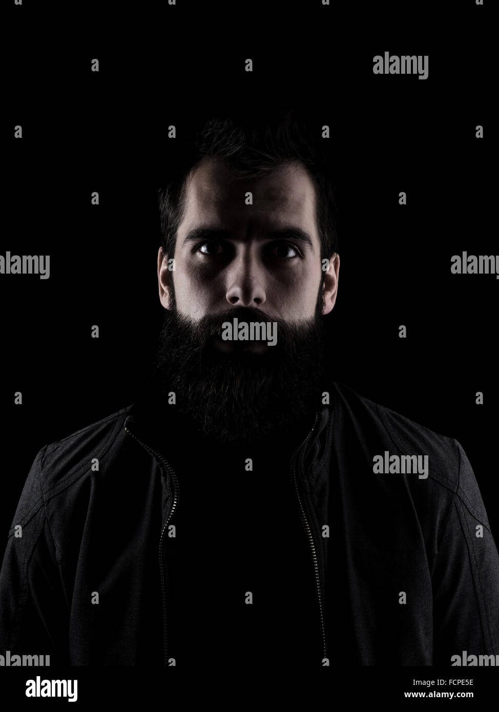 Scary bearded man staring at camera. High contrast low key dark shadow ...