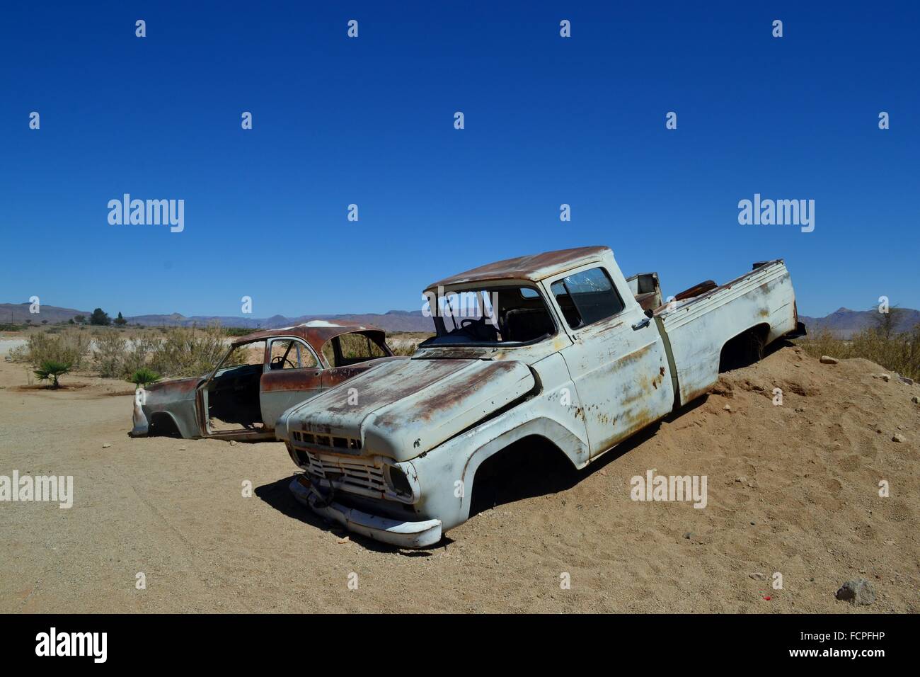 Abandoned, rusting and wrecked old pickup truck and car in a desert ...