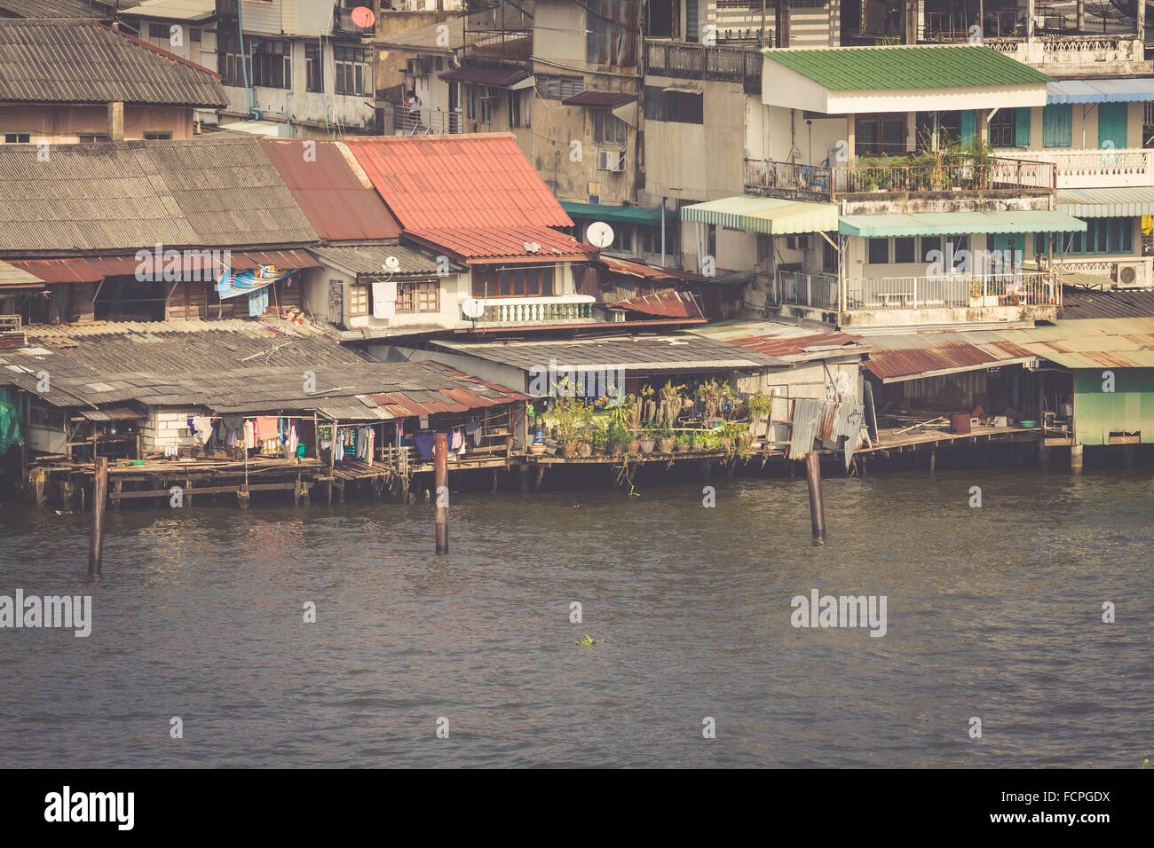 Wooden slums on stilts on the riverside of Chao Praya River in Bangkok ...