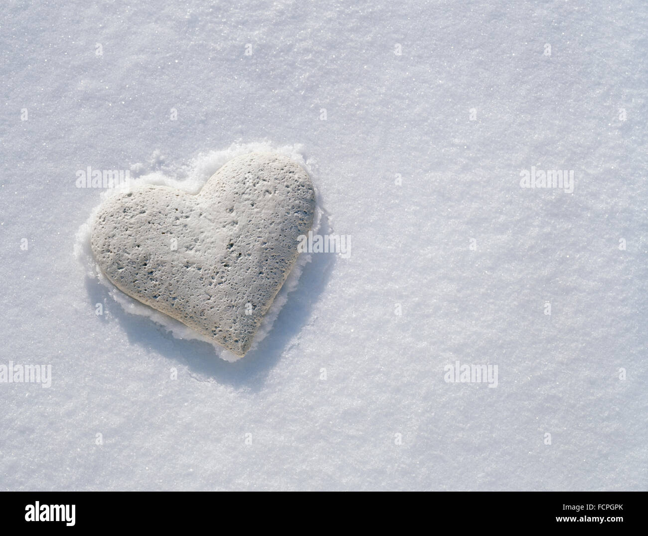 White stone heart resting on frozen crust of pristine snow Stock Photo ...