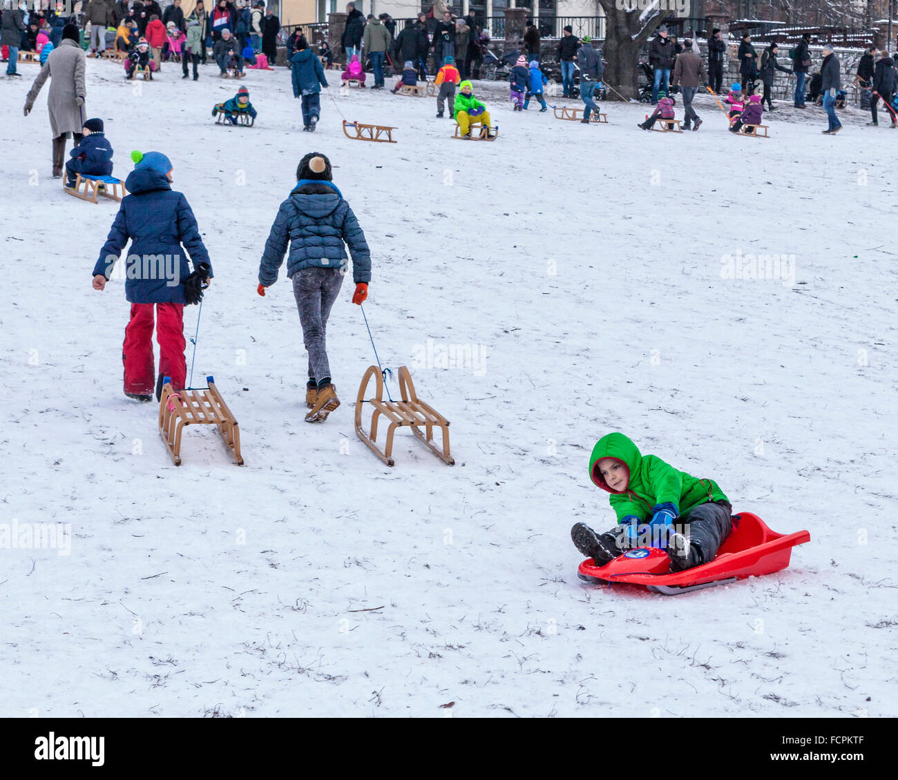 Families & children with sleds on a snowy slope in a public park in ...