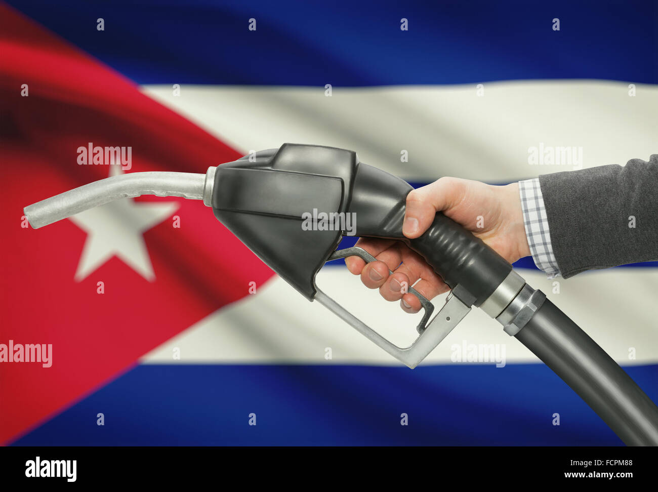Fuel pump nozzle in hand with flag on background - Cuba Stock Photo - Alamy