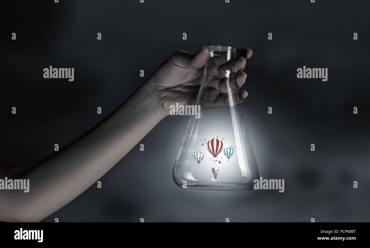 Hand holds flask with images on varied background Stock Photo - Alamy