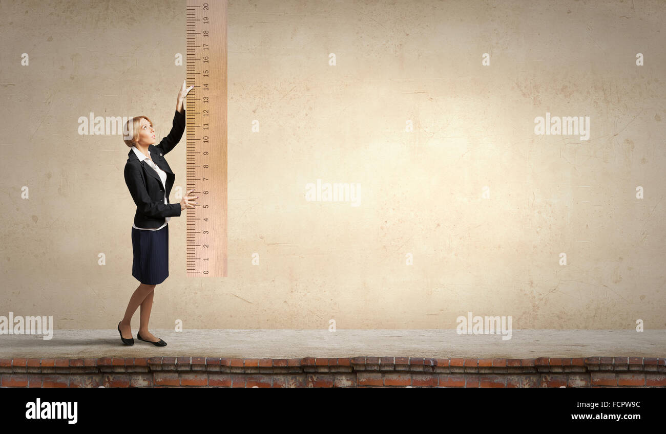 Young businesswoman measuring something with big ruler Stock Photo - Alamy