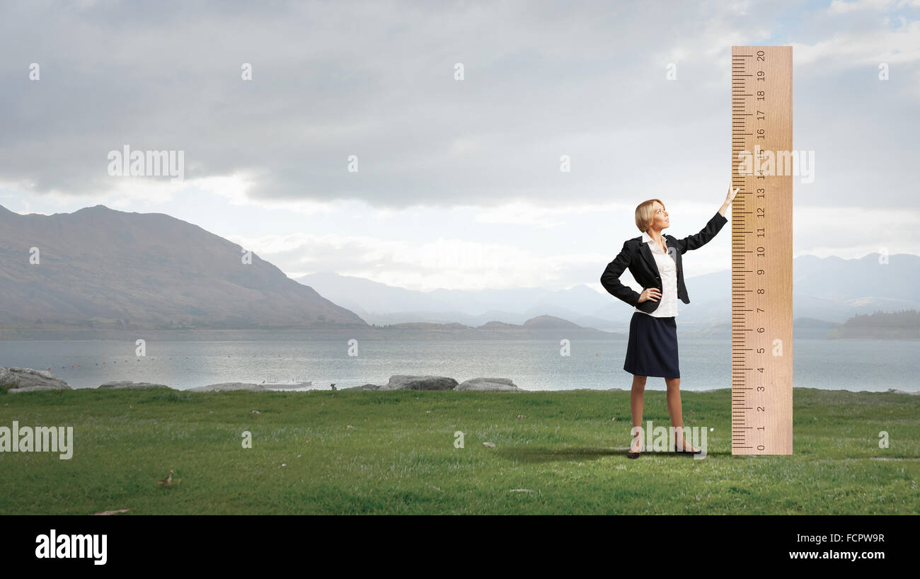 Young businesswoman measuring something with big ruler Stock Photo - Alamy