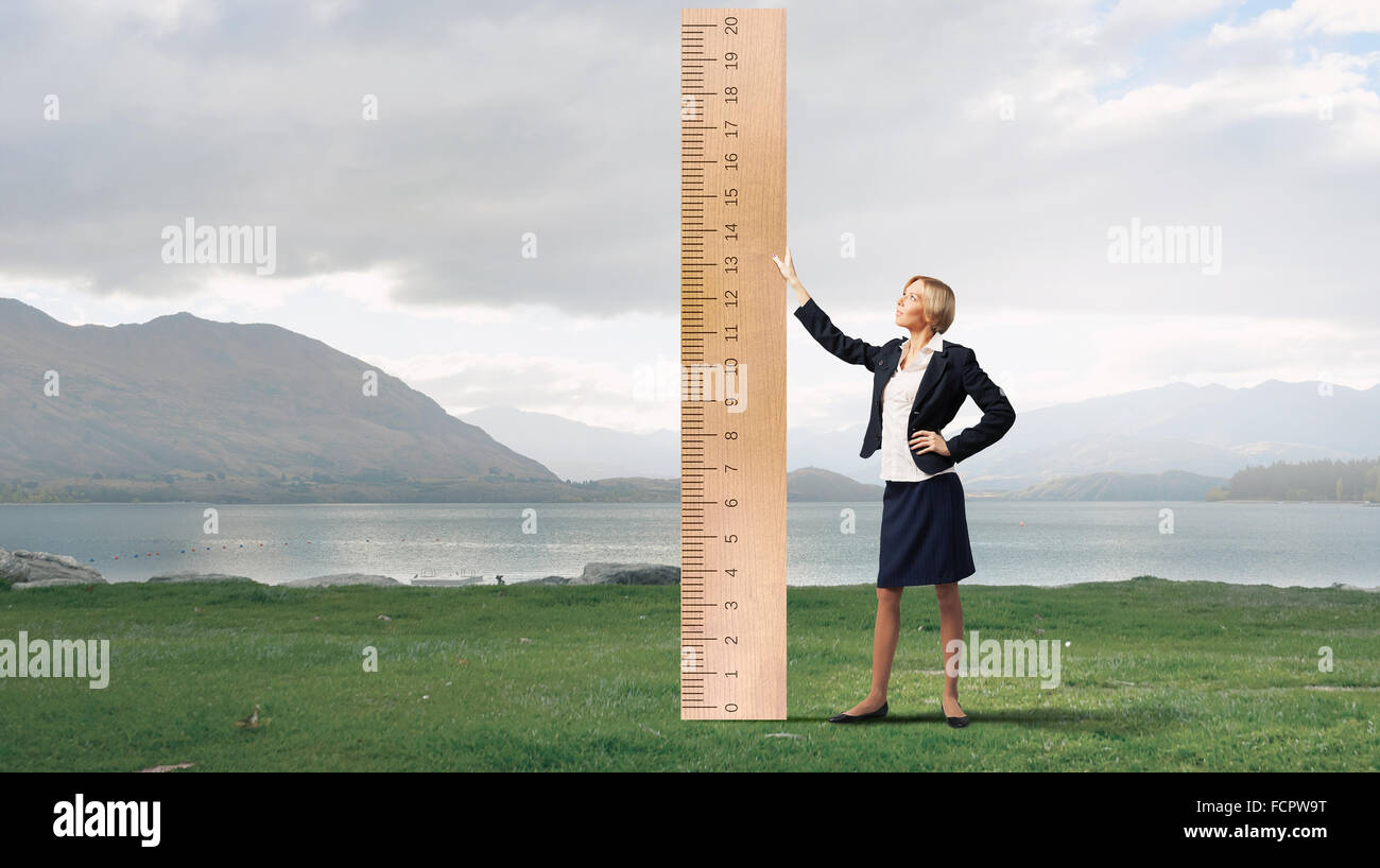 Young businesswoman measuring something with big ruler Stock Photo - Alamy
