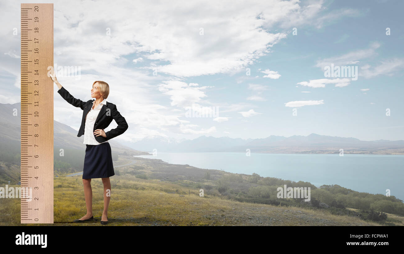 Young businesswoman measuring something with big ruler Stock Photo - Alamy