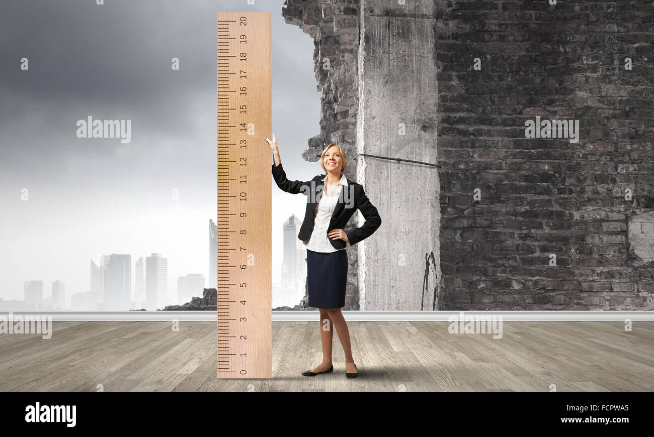Young businesswoman measuring something with big ruler Stock Photo - Alamy