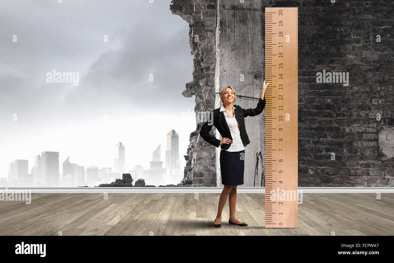 Young businesswoman measuring something with big ruler Stock Photo - Alamy