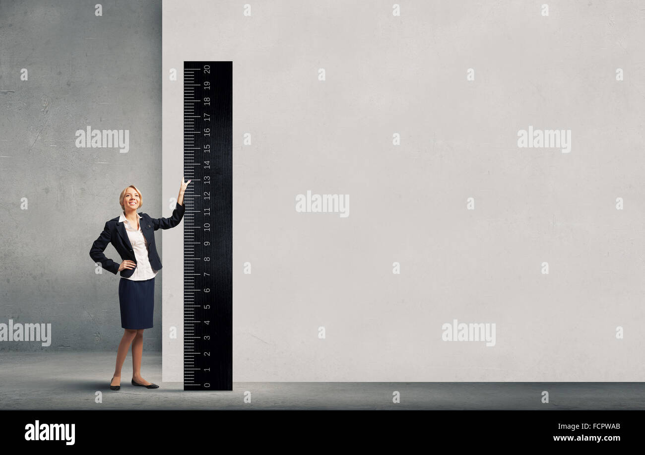 Young businesswoman measuring something with big ruler Stock Photo - Alamy