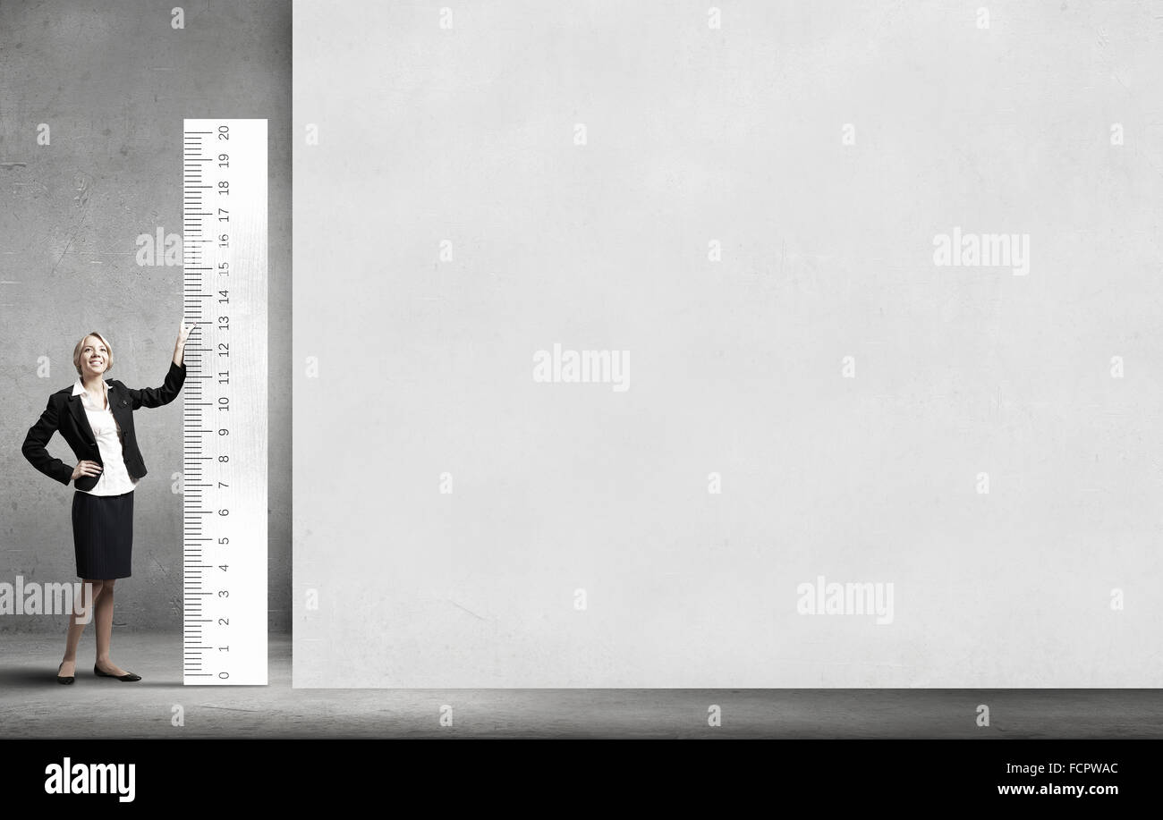 Young businesswoman measuring something with big ruler Stock Photo - Alamy