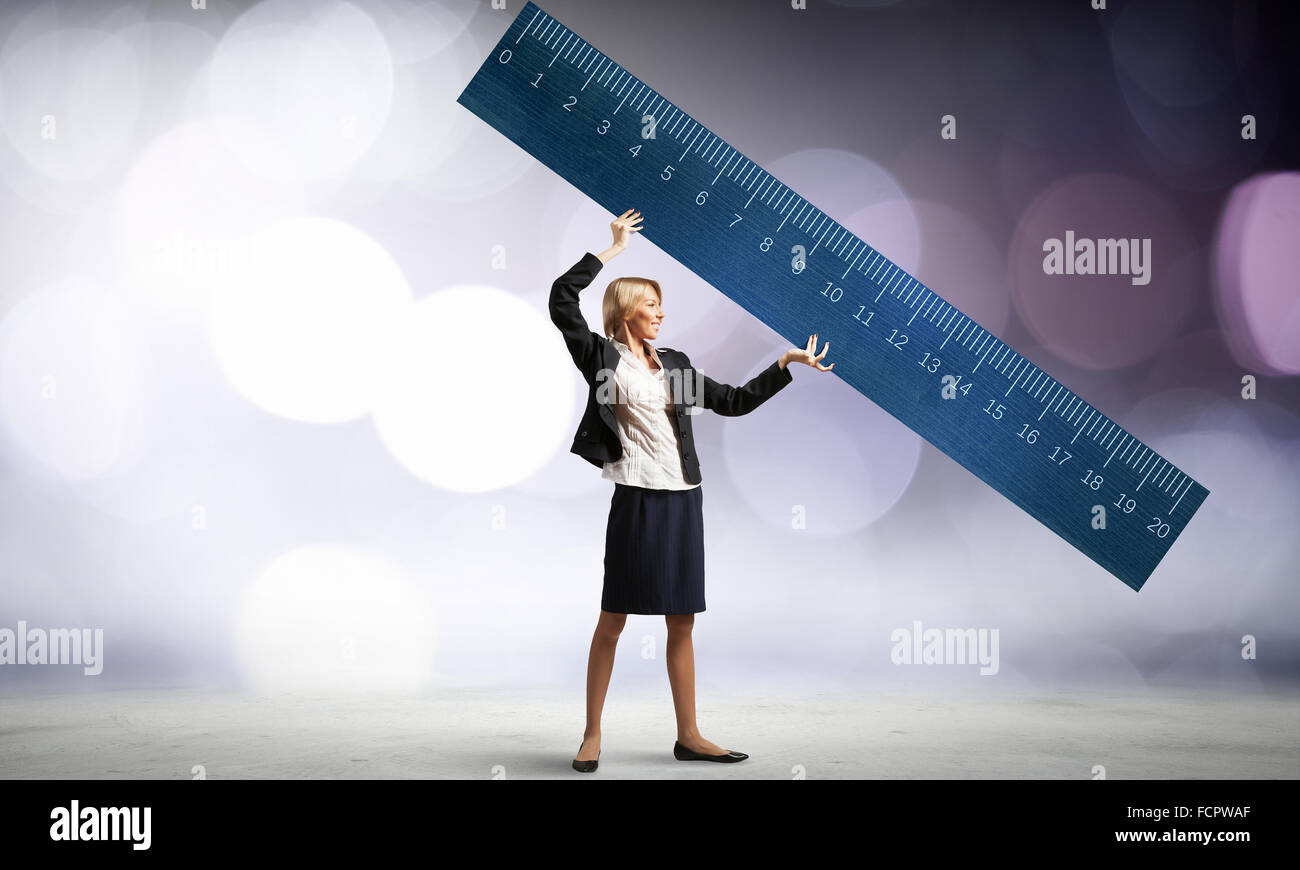 Young businesswoman measuring something with big ruler Stock Photo - Alamy