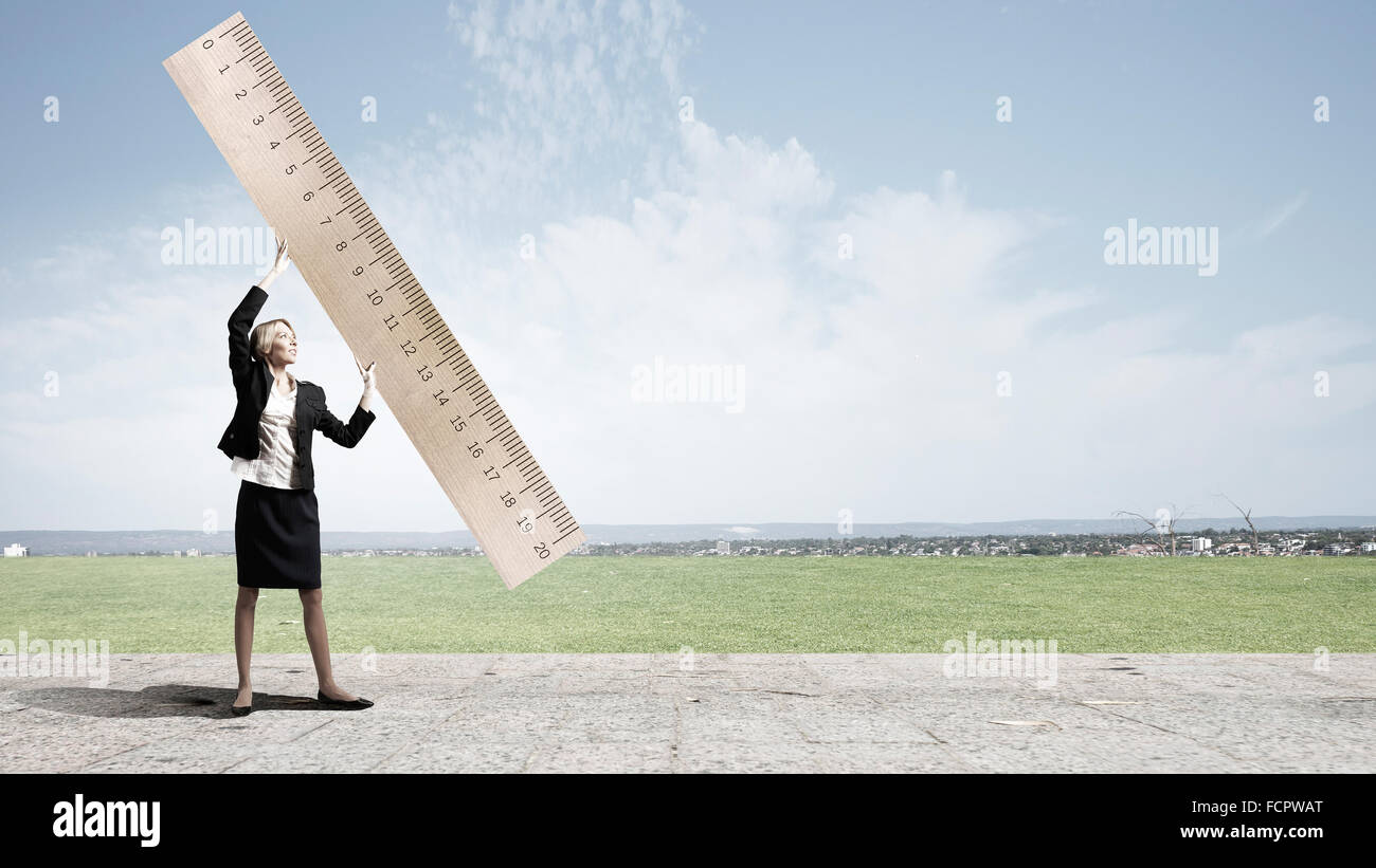 Young businesswoman measuring something with big ruler Stock Photo - Alamy