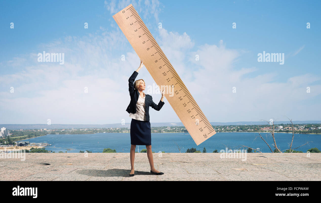 Young businesswoman measuring something with big ruler Stock Photo - Alamy