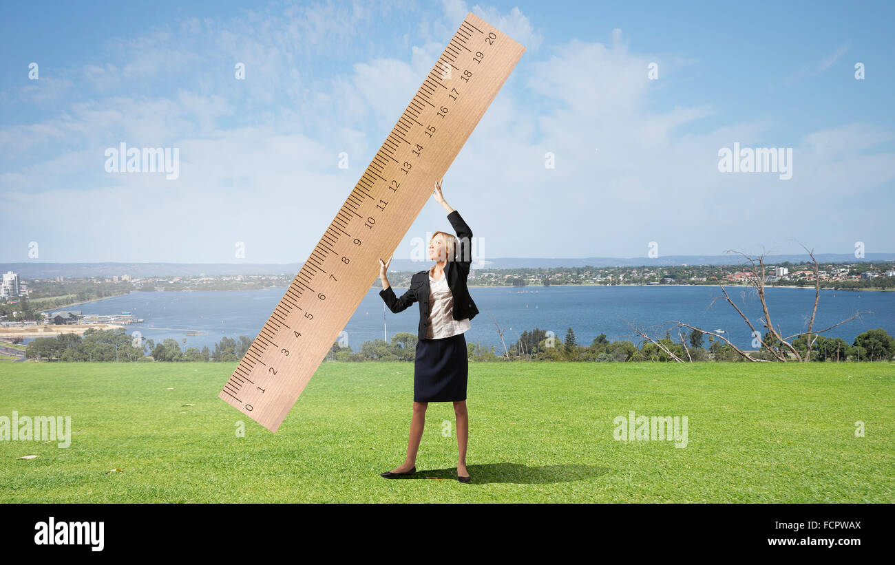 Young businesswoman measuring something with big ruler Stock Photo - Alamy