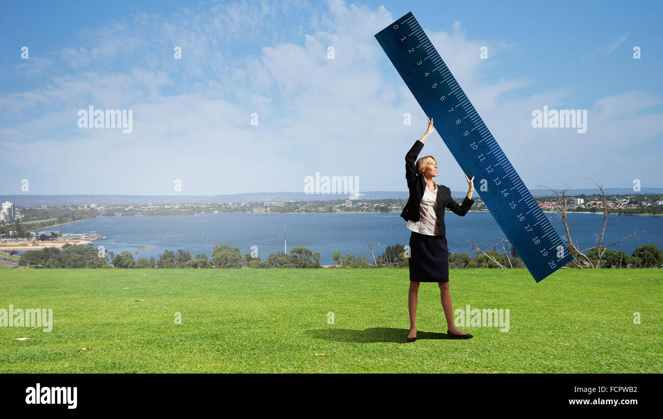 Young businesswoman measuring something with big ruler Stock Photo - Alamy