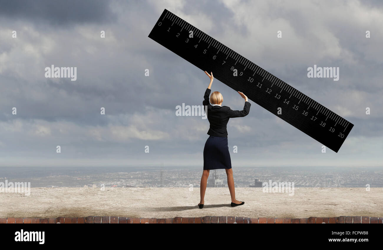 Young businesswoman measuring something with big ruler Stock Photo - Alamy