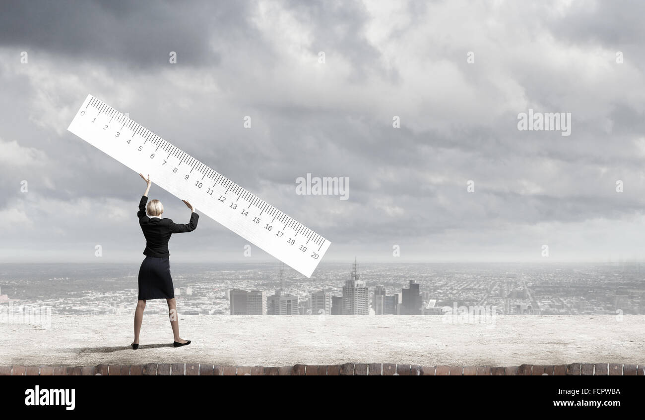 Young businesswoman measuring something with big ruler Stock Photo - Alamy